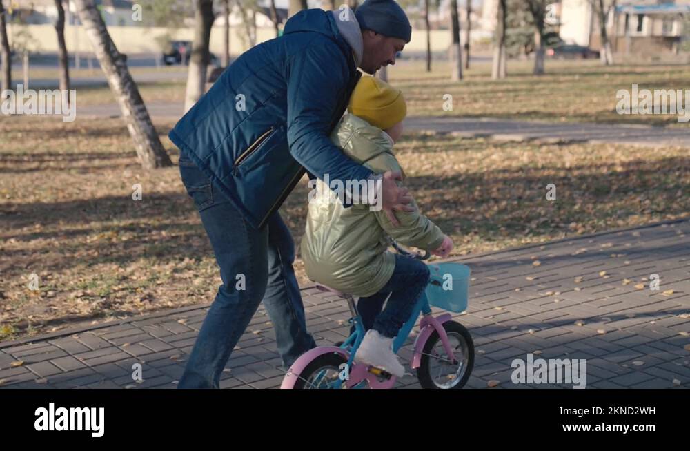 joyful father teache little child ride two-wheeled bike happy family ...
