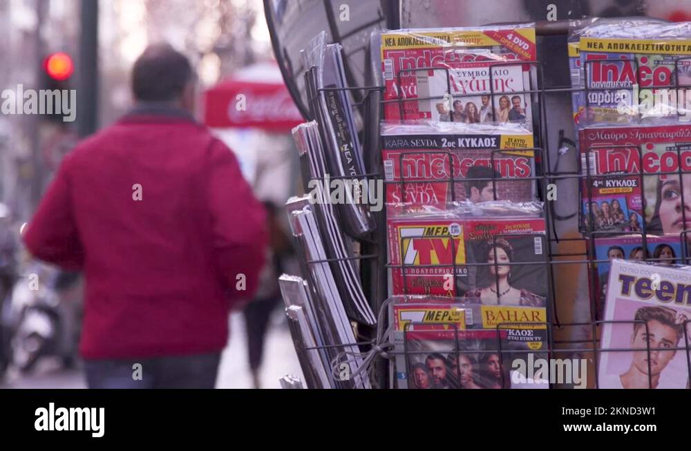 Man running past magazines at newspaper stand in the center of Athens ...