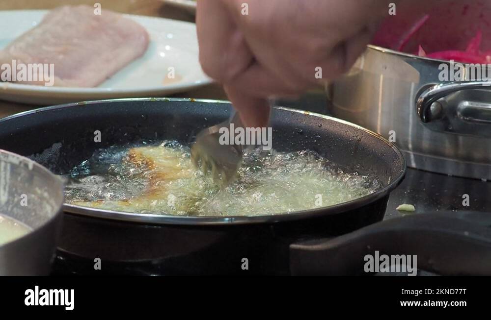 The cook flips two pieces of toasted fish while they fry in a pan Stock ...