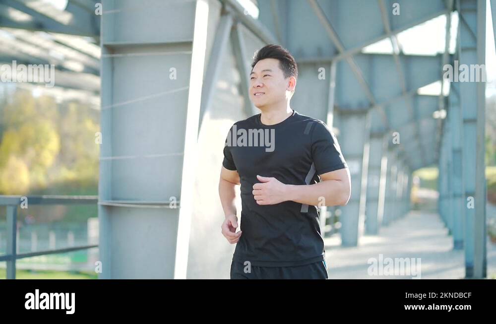 young asian runner running on modern urban stadium background. Morning ...