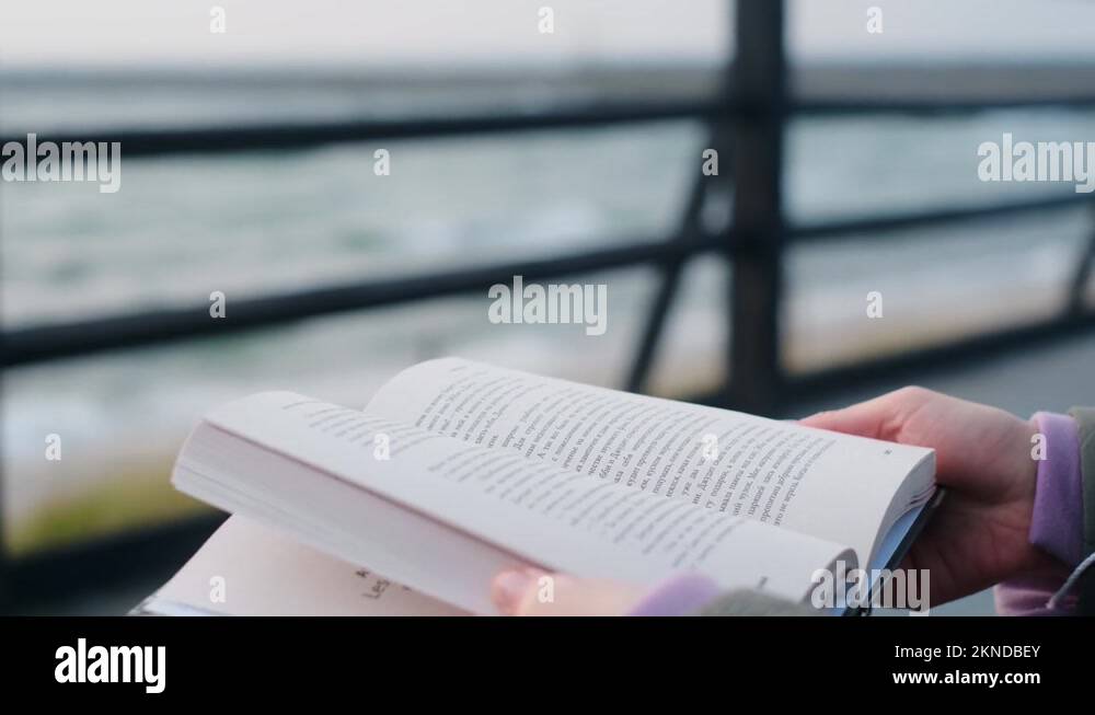 Wind turns the book pages in slow motion. Open book lies on the bench ...