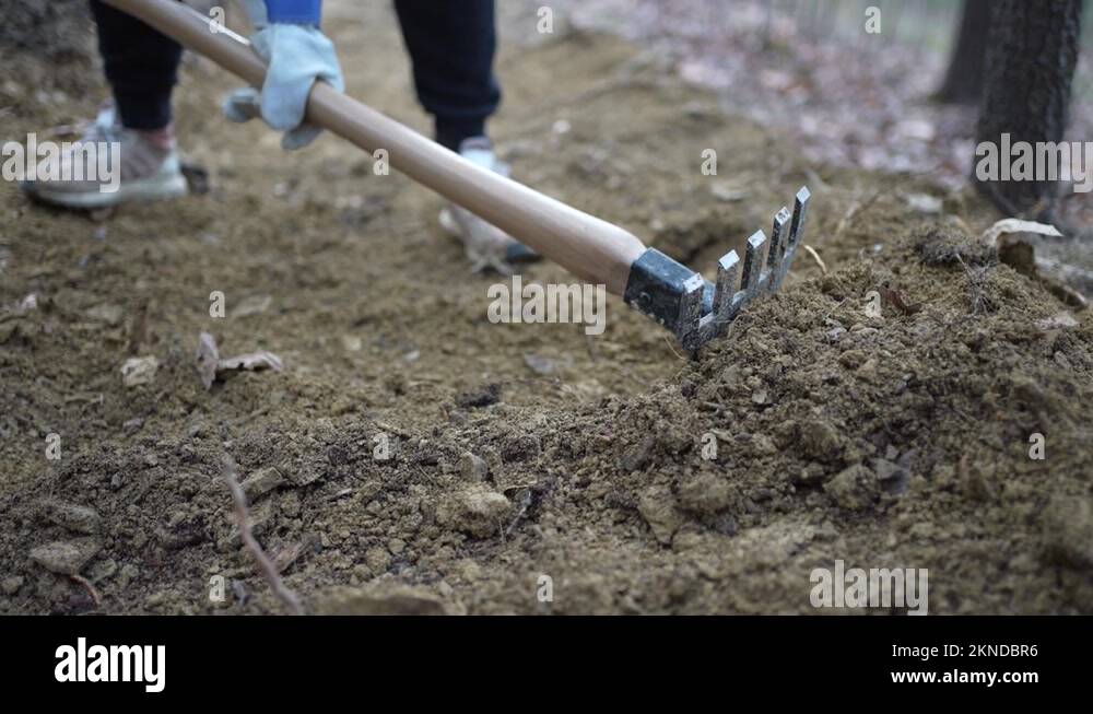 Closeup of hoe pushing dirt across hiking trail with metal hoe, cut ...