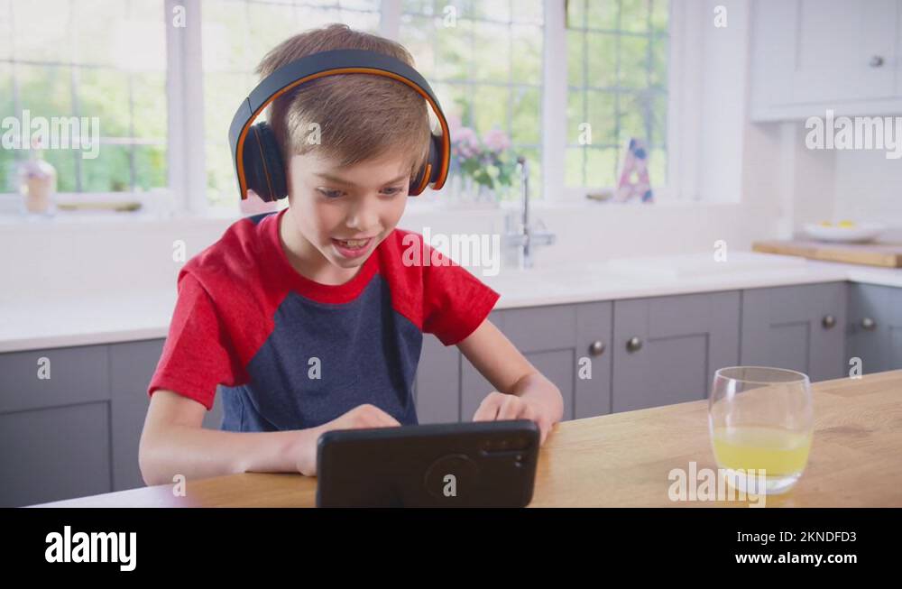 Boy At Home In Kitchen Watching Movie Or Show On Mobile Phone Wearing ...