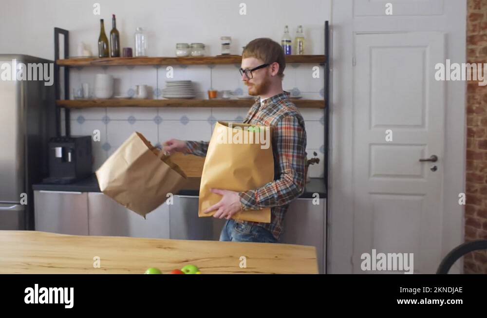 Man unpacking fresh food delivery from market in kitchen. Real time ...
