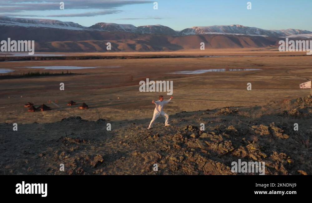 Video of wushu master in a white uniform training on the hill at sunset ...