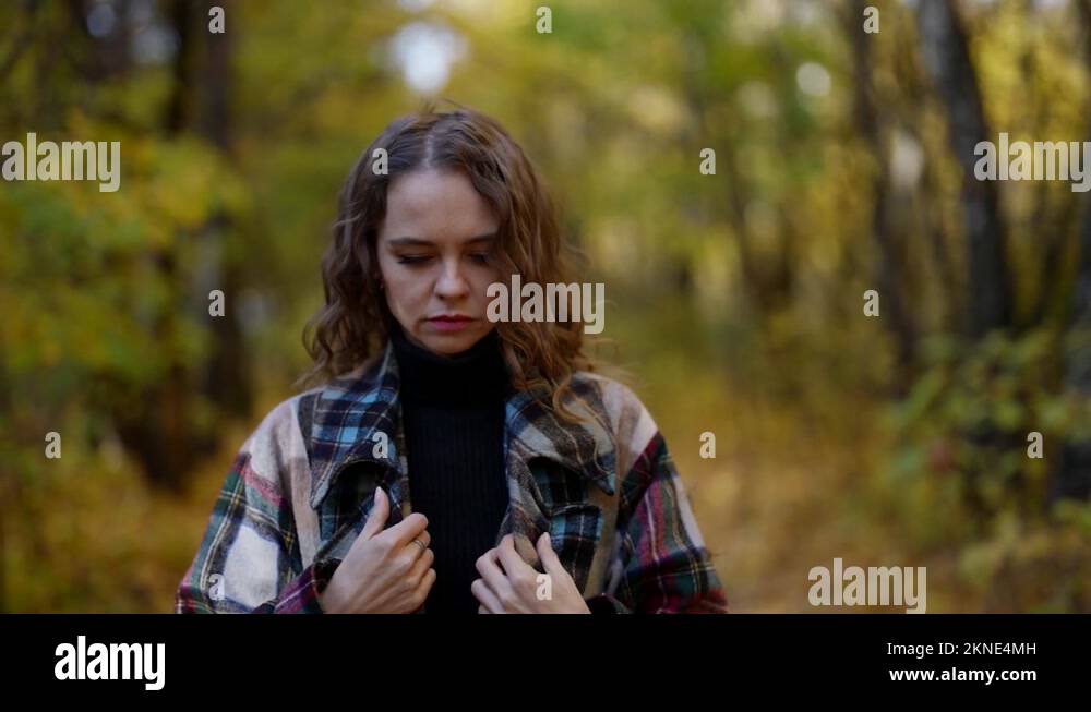 sad woman is walking alone in forest and dry foliage is falling on her ...