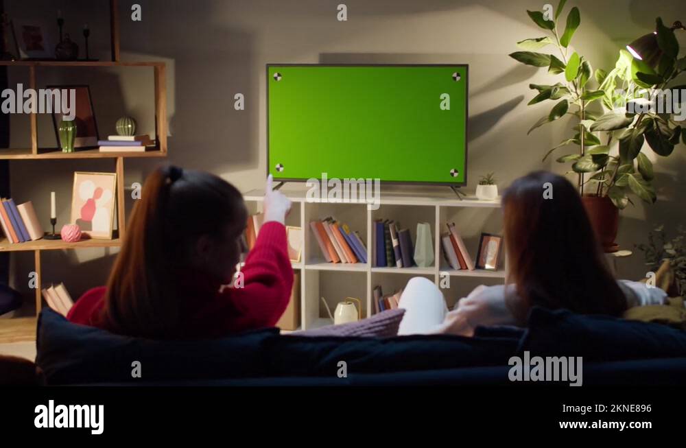 Women watching television with chroma green screen. Girlfriends showing ...