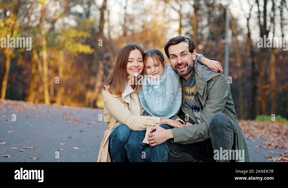 Young smiling mom, dad and little daughter are hugging while sitting squatting Stock Video ...