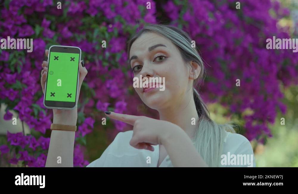 Woman in front of blooming tree,pointing finger at screen of green ...
