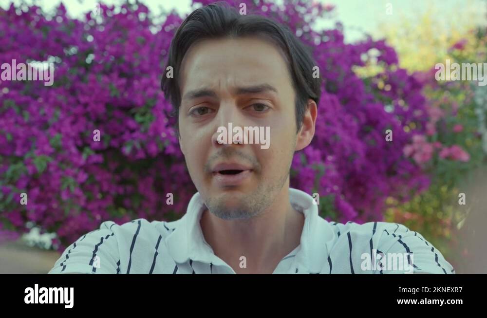 Young angry man making a video call on her smartphone near a flowering ...