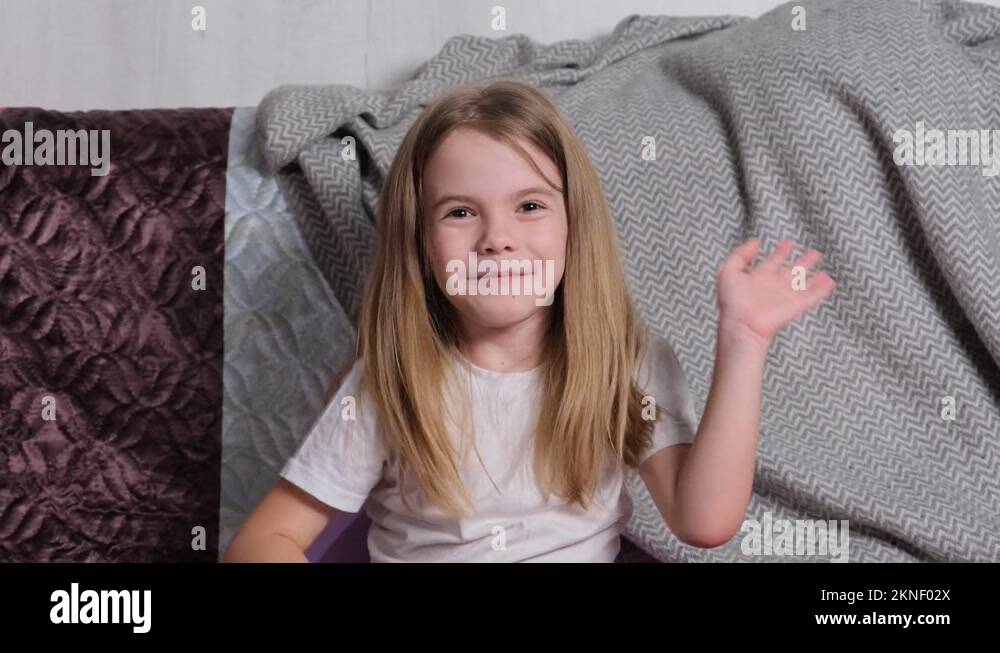Little girl smiling looking at camera at home, making online video call ...