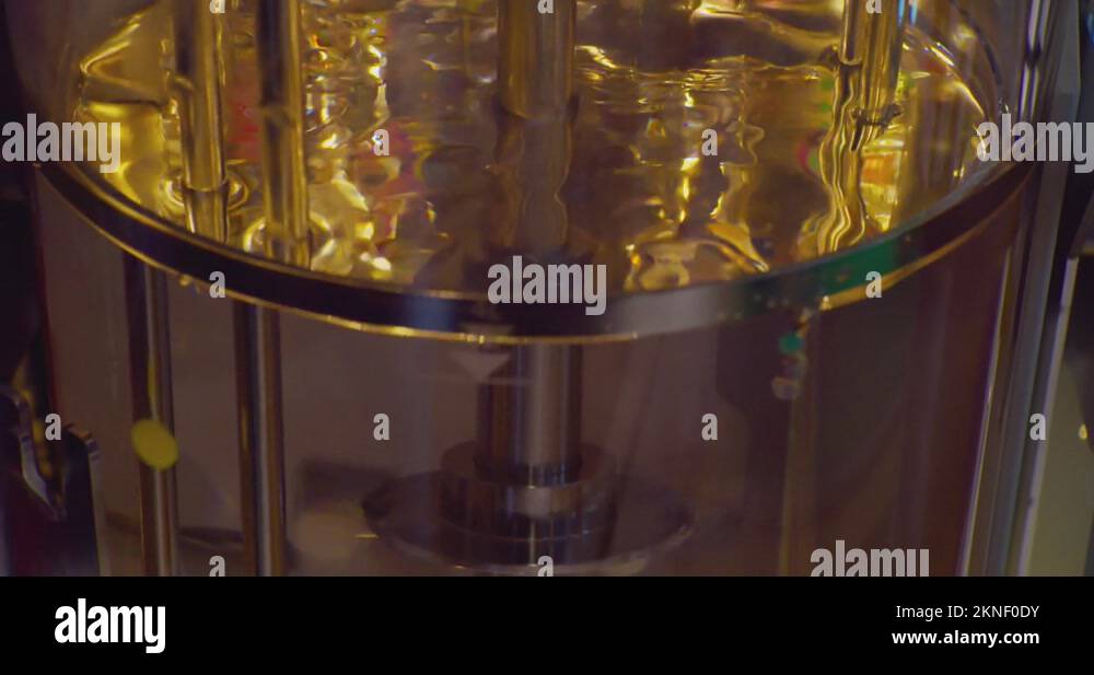 liquid molten metal is stirred in a transparent glass flask.close-up ...