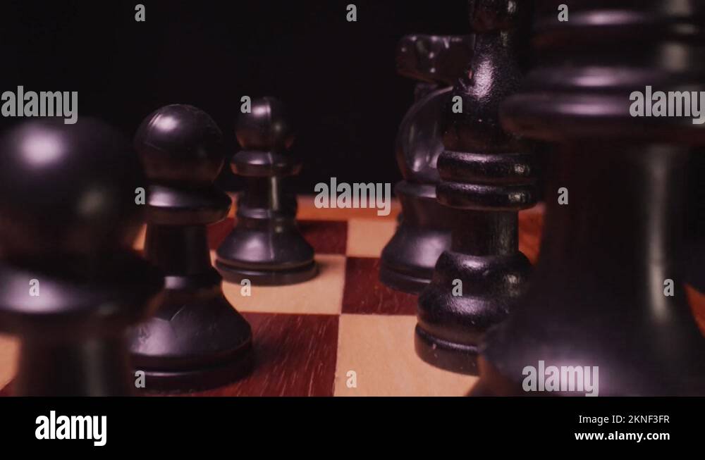 Camera zooming out through rows of black chess pieces on a wooden chess ...