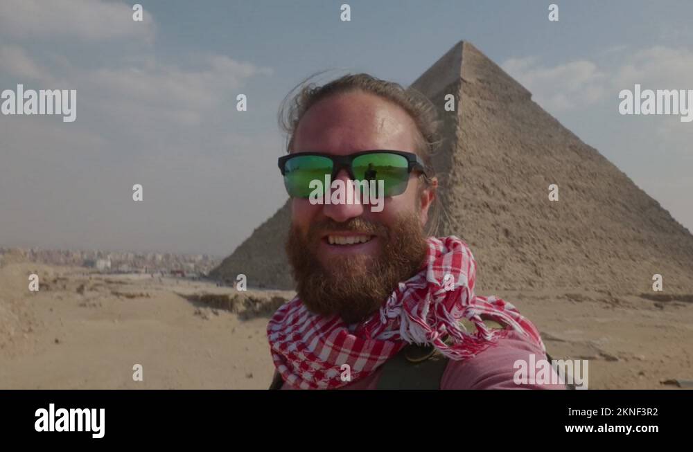 Young man sightseeing the Great Pyramids of Giza takes cool selfies ...