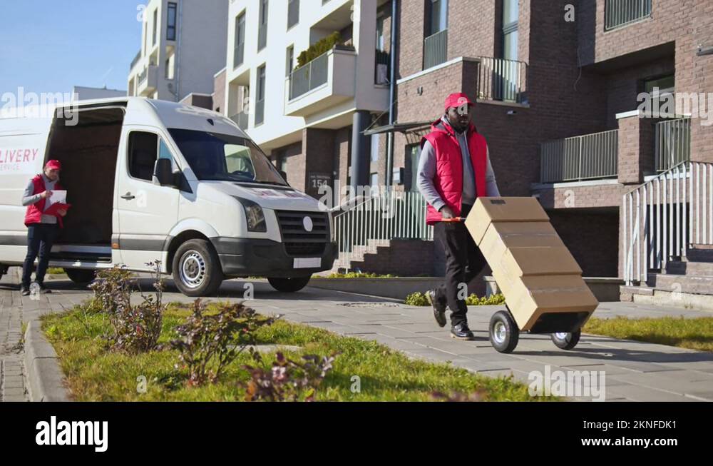 African american delivery man carring parcel boxes on a trolley from a ...