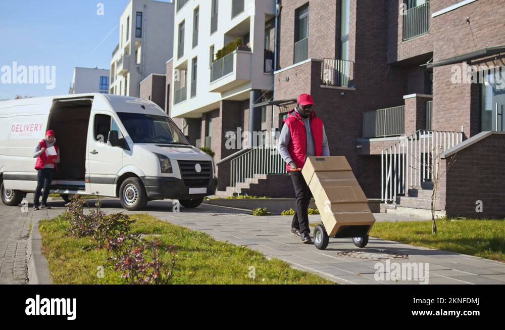 African american delivery man carring parcel boxes on a trolley from a ...