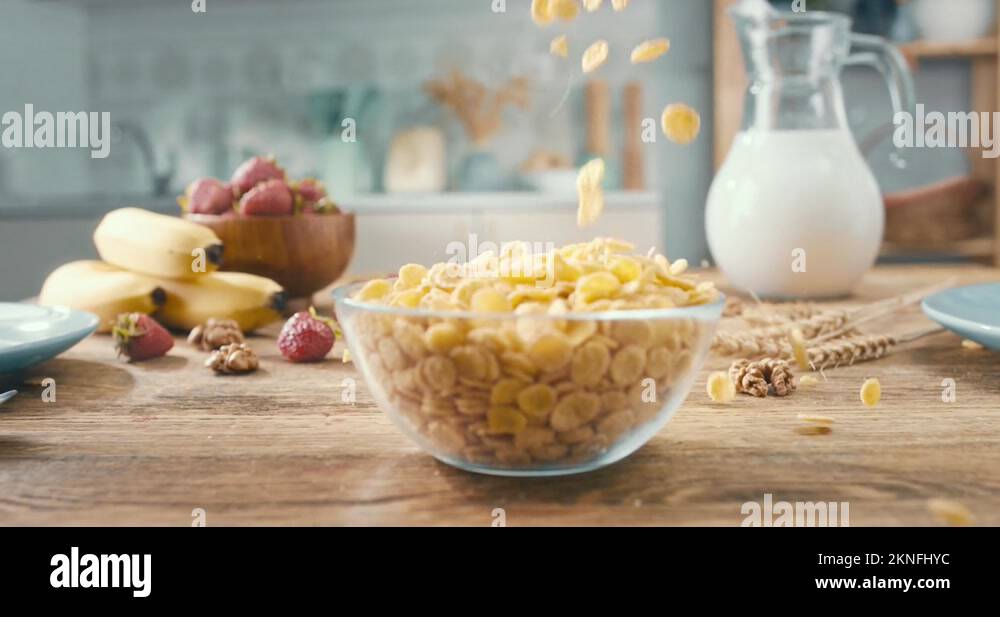 Sweet crusty corn flakes falling into glass bowl. Crispy vegan cereal ...