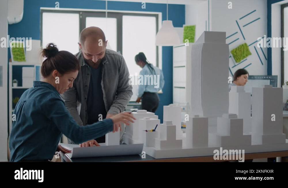 Man And Woman Analyzing Blueprints Plan And Building Model To Design Urban Stock Video Footage