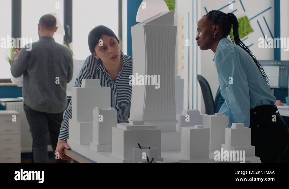 Team of architects working with building model and maquette to plan ...