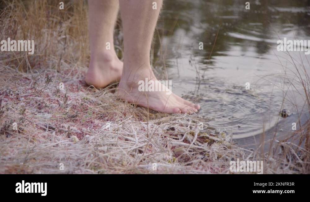 REVEAL CLOSEUP - Ice bathers feet approach and start breaking the ice ...