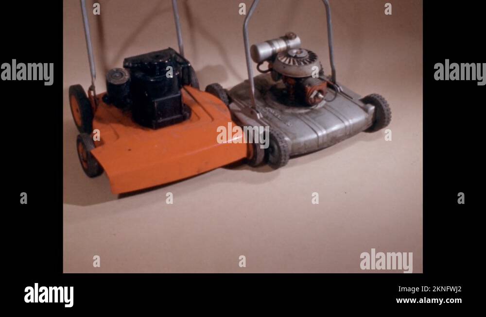 1960s: Two lawn mowers side by side, one orange and shiny, the other ... 1960s: Two lawn mowers side by side, one orange and shiny, the other ...