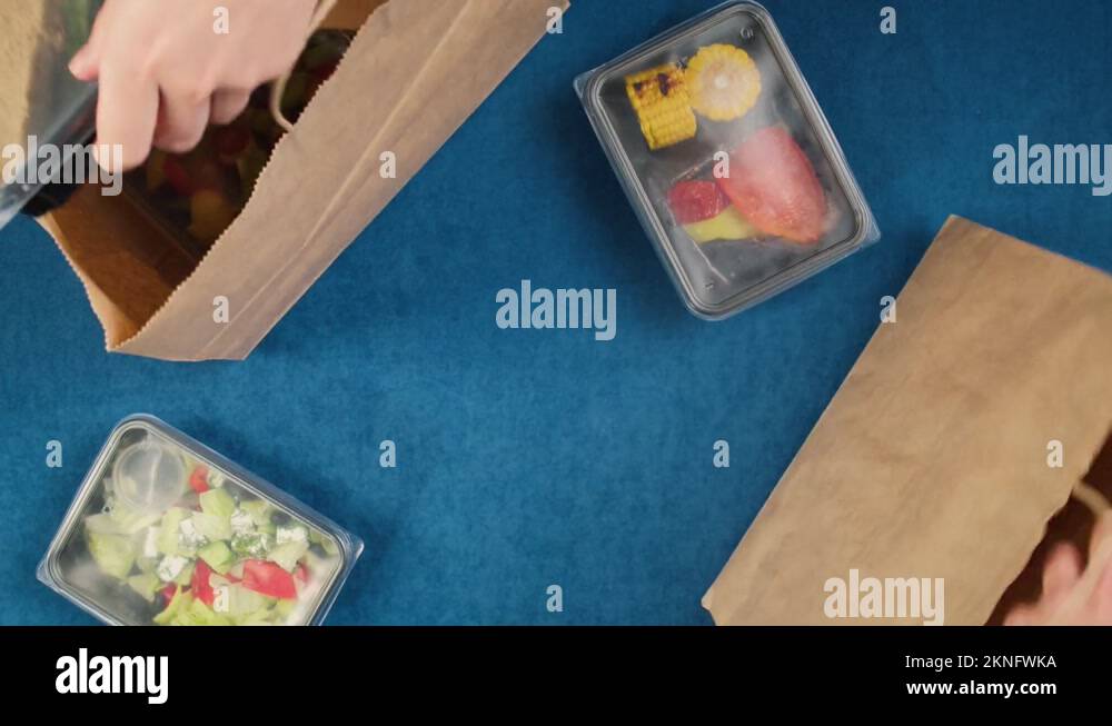 Taking food delivery in disposable containers from paper bags top view ...