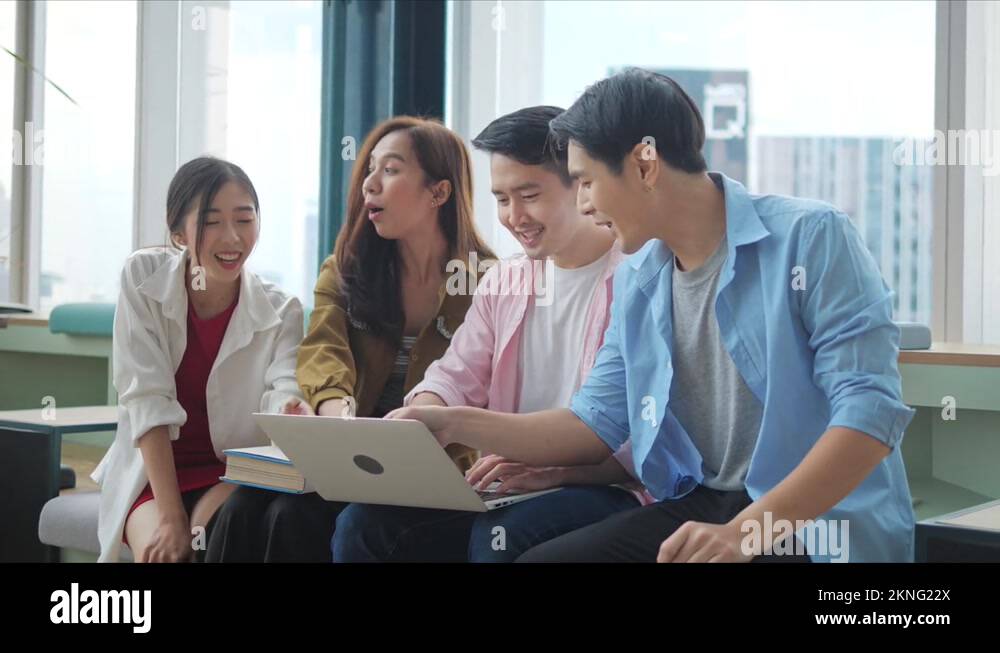 A group of Asian high school students meets in an office boardroom to ...