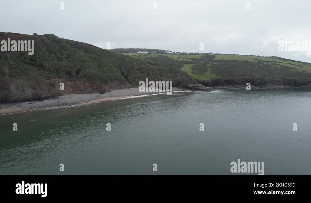 Waves calmly washing beach at coast, high and steep rocky cliff Stock ...