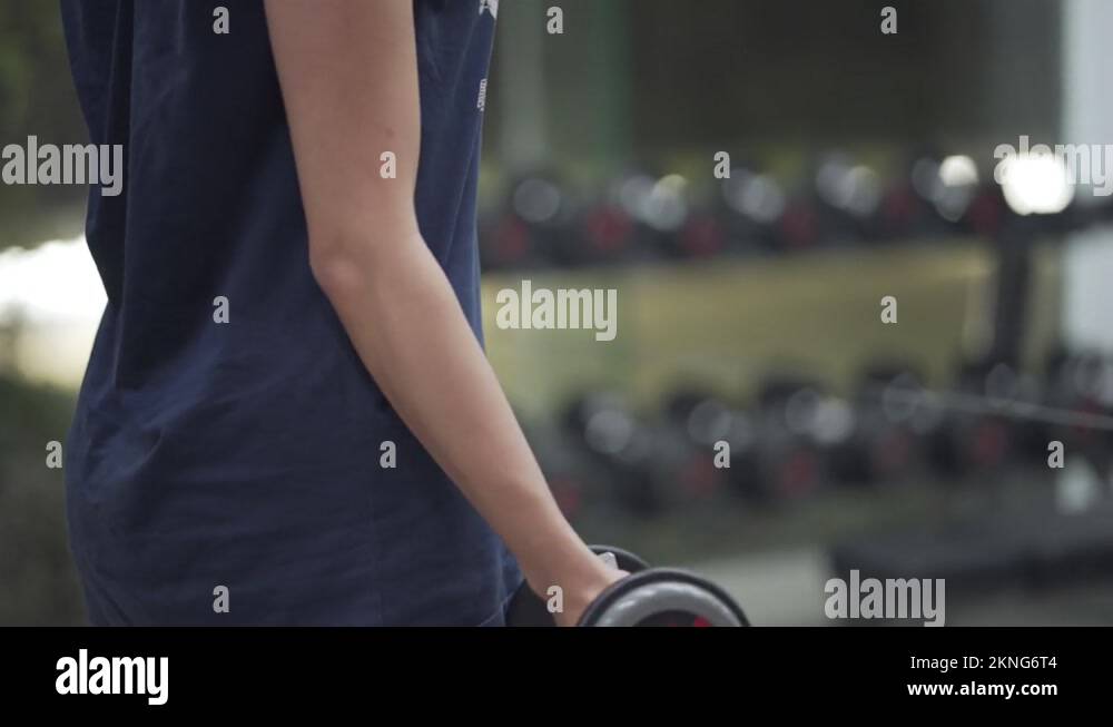 Female fit body concentrating on doing a dumbbell curls at modern gym ...