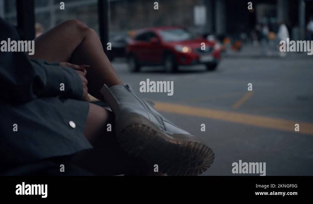 Female legs bus stop in city background. Girl waiting for ride in urban ...