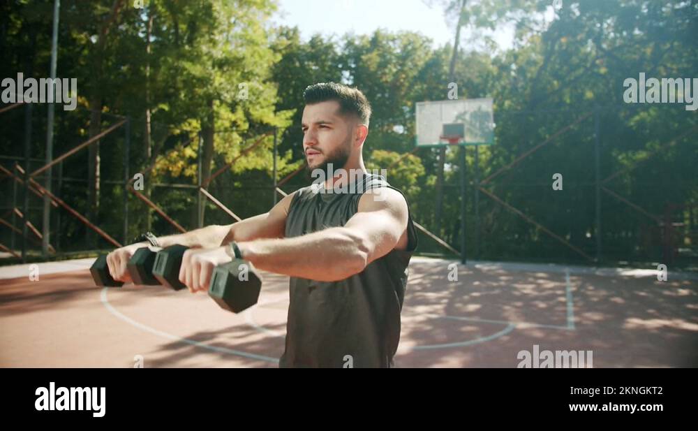 Sporty man lifting weights with both hands in a public park, Biceps ...