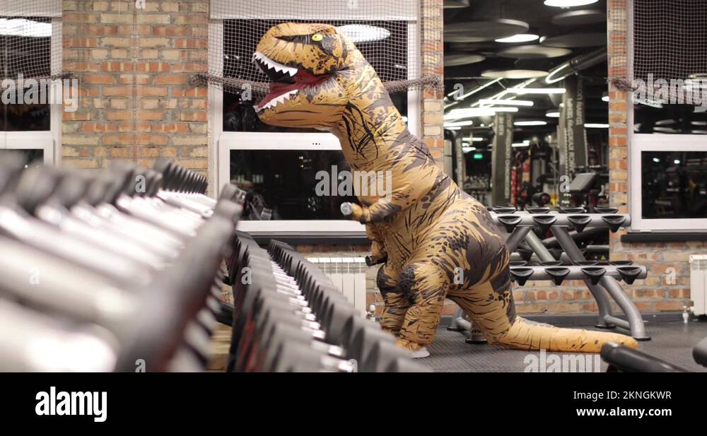dinosaur doll with person inside in the gym, trains, does biceps ...