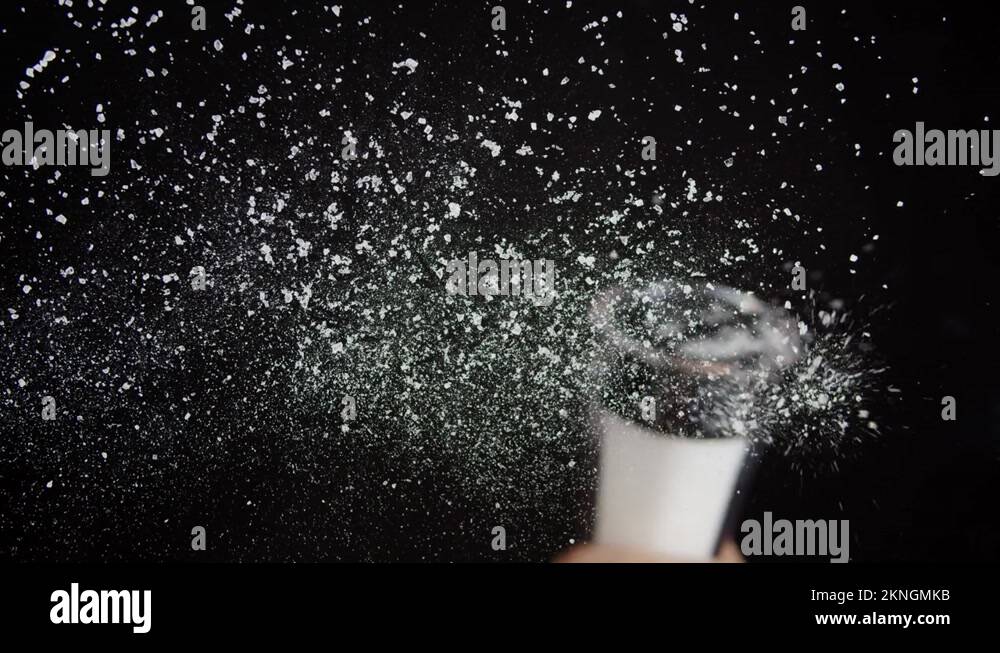 Salting food close-up. Salt falling on glass on black background, using ...