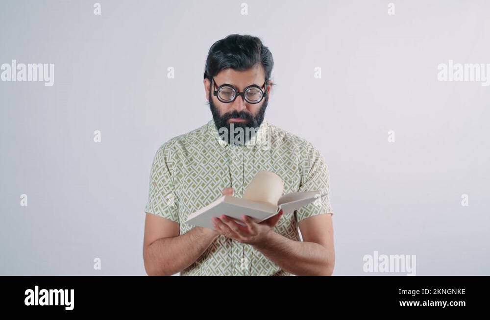Young Indian Asian male nerd wearing eyeglasses standing and reading a ...