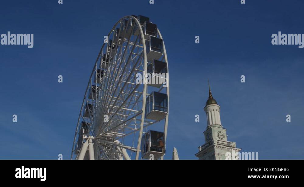 spinning Ferris wheel and a bell tower against a blue cloudless sky ...