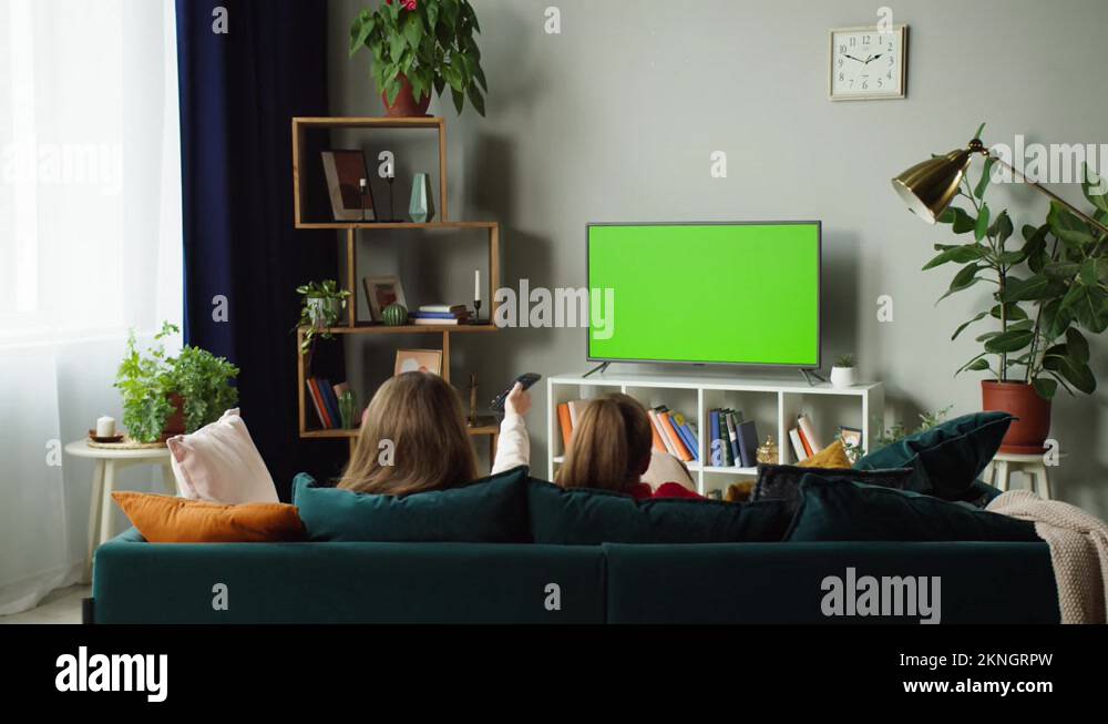 Women watching television with chroma green screen. Girlfriends ...