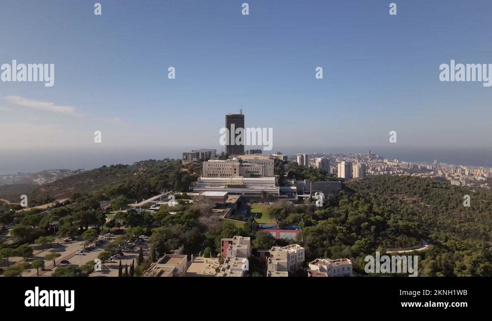 Tall building on green hills with trees in the background Haifa city ...