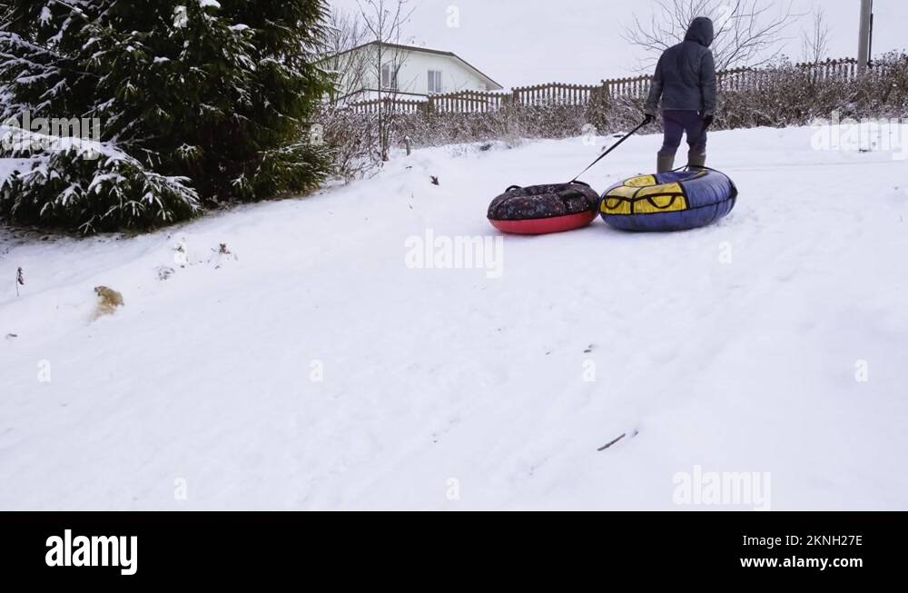 The man go with two tubing to the top of the snow slide. Outdoor winter ...