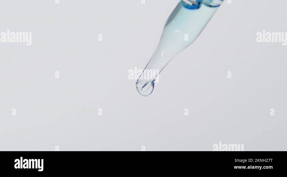 Transparent liquid falling from glass pipette, close up view isolated ...