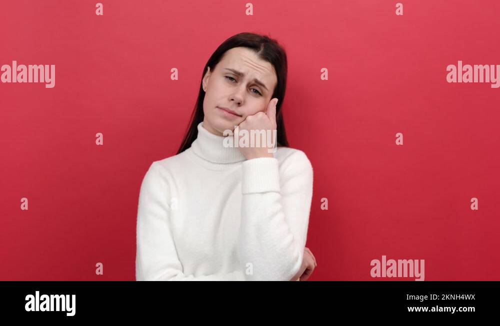 Portrait of unhappy tired young woman standing with face in hand ...