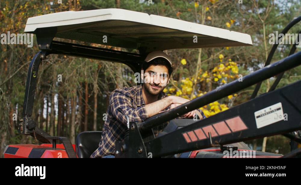 Young man smiling looking at the camera while sitting an agricultural ...