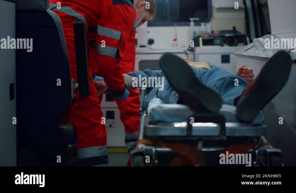 EMS paramedics treating patient with wound on hand in emergency car ...