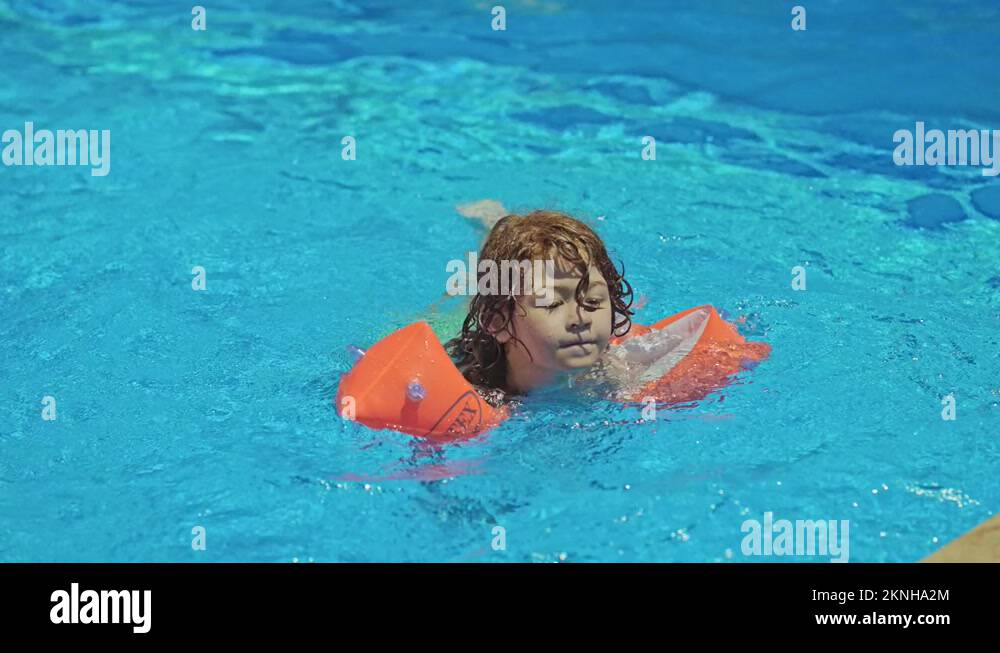 Little boy tries to swim in the pool with an inflatable rubber ring ...