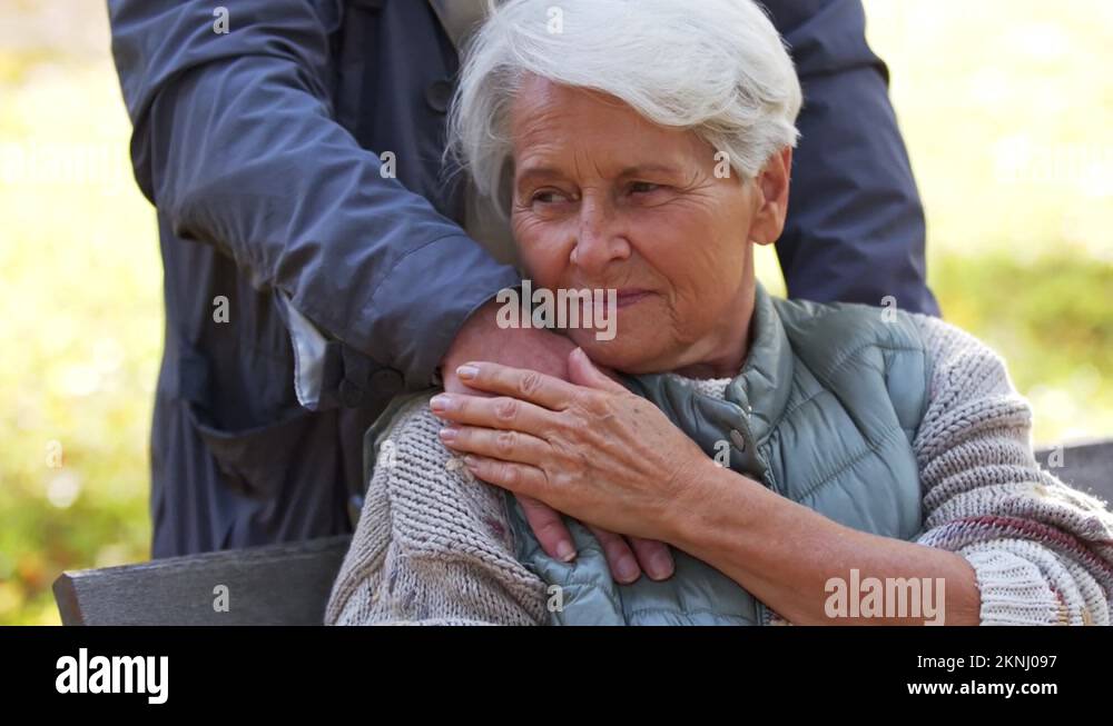 Elderly couple in the park. Man placing his hand over the shoulder of a ...