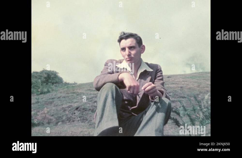 1950s: Clapboard, shots of man sitting on ground, picking at leaves ...