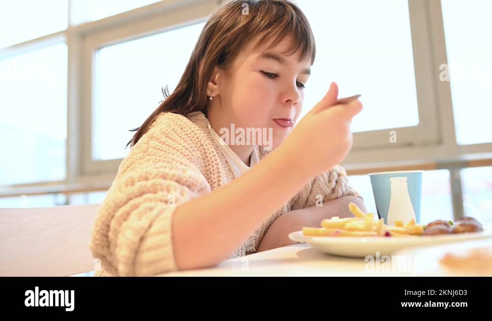 girl, child eating fries, fast food in a restaurant in a shopping mall ...