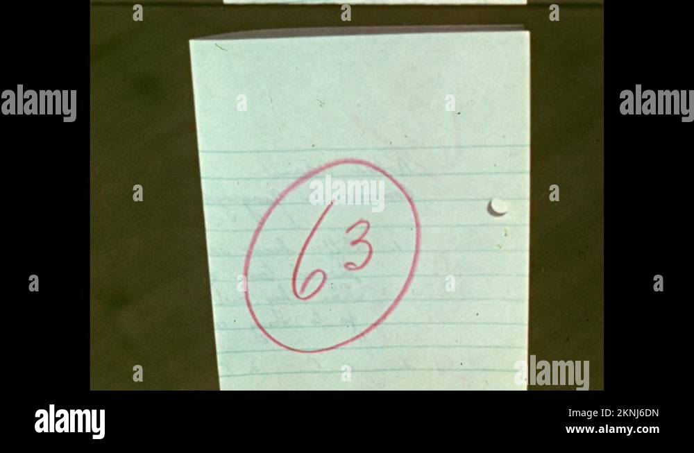 1950s: Slate. Circled 63 written on a lined paper. Slate. Hands place a ...