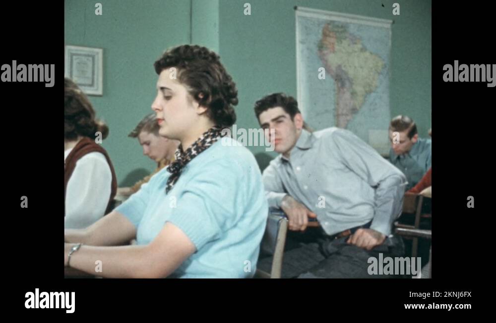 1950s: Clapboard snaps. Teenagers sitting in a classroom. Teen boy ...