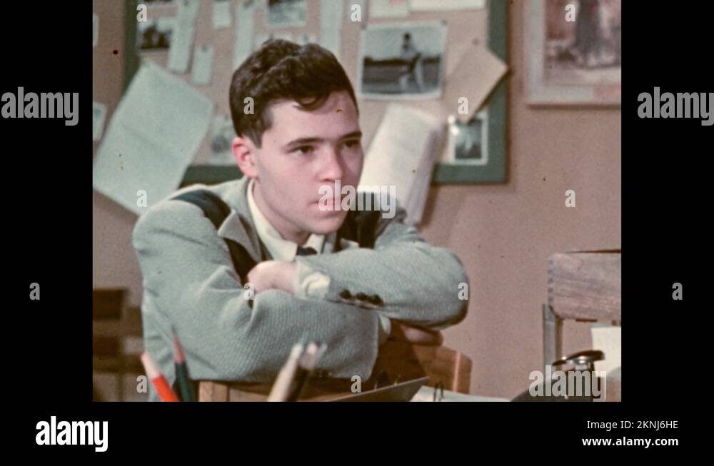 1950s: Film slate. Boy sitting the wrong way in a chair. Girl hands boy ...