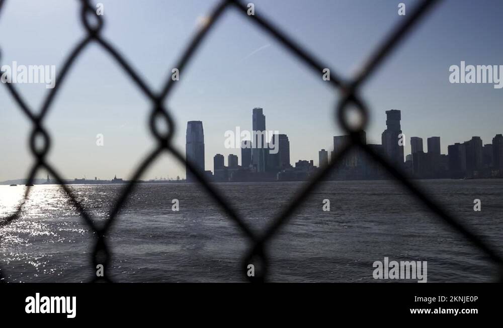 New York City skyline at distance behind steel mesh wire fence during a ...